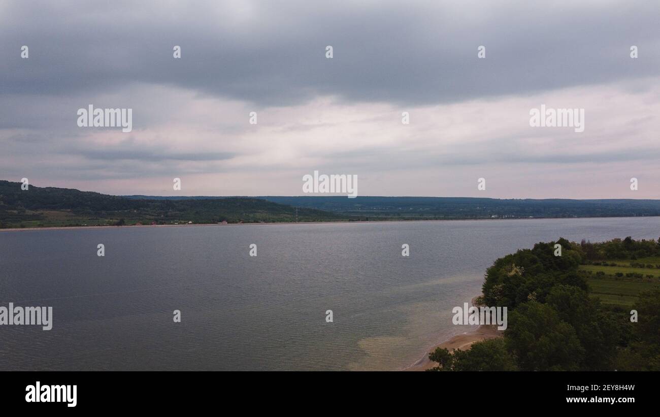 An aerial of a landscape with a flowing river gleaming under the cloudy ...