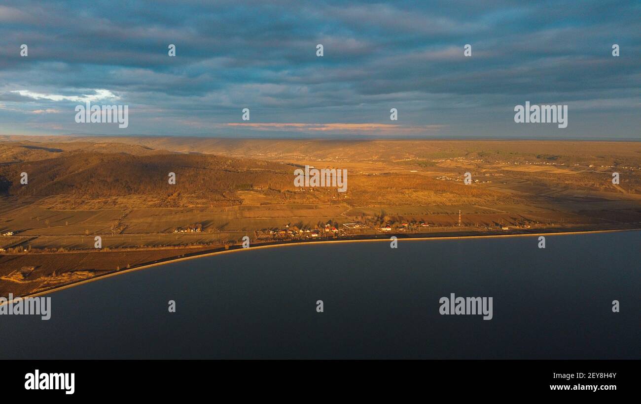 An aerial of a landscape with a flowing river gleaming under the cloudy ...