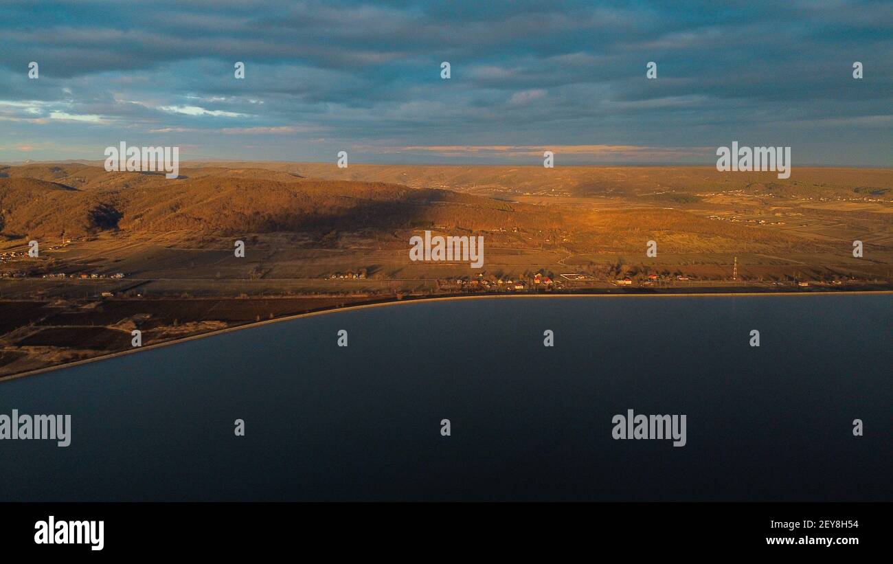 An aerial of a landscape with a flowing river gleaming under the cloudy ...