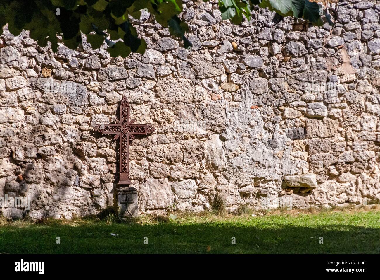 A rusty metal cross against a bright white stone wall Stock Photo - Alamy