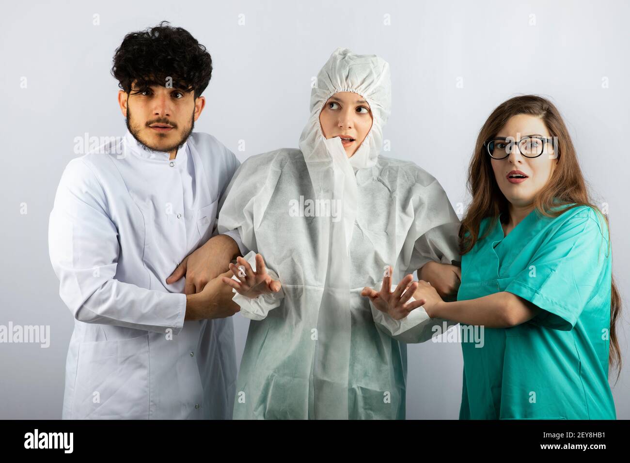Three doctors standing and looking at camera on white background Stock ...