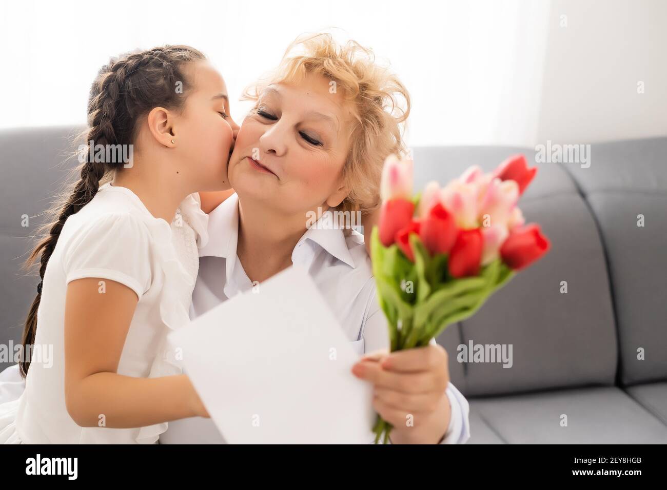 Sincere cute little granddaughter strong cuddling and kissing in cheek ...