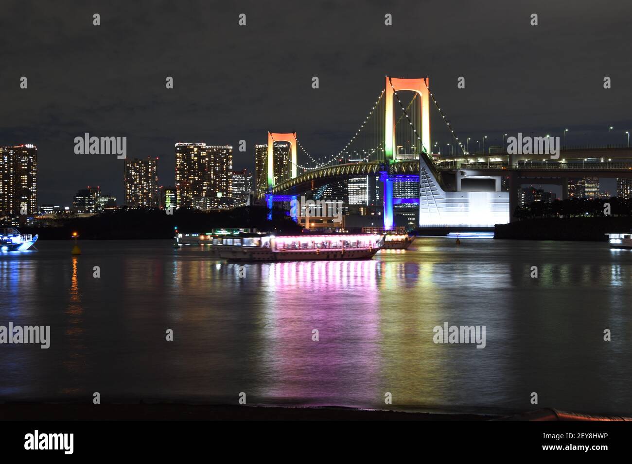 The Rainbow Bridge over a river in Tokyo, Japan at night Stock Photo ...