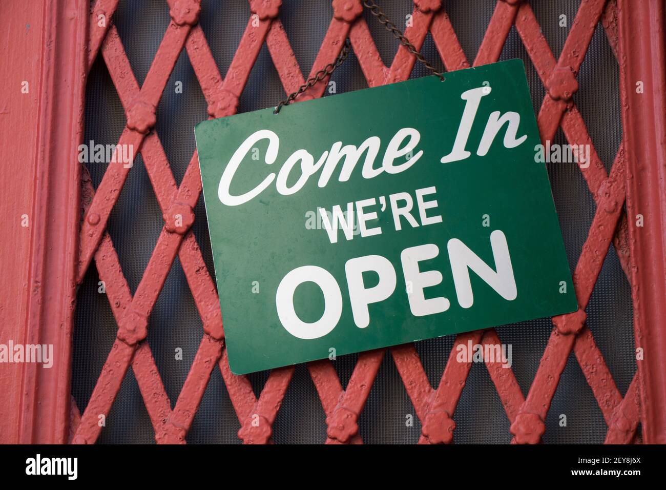 A green Come In We are Open sign hanging from a metal door Stock Photo ...