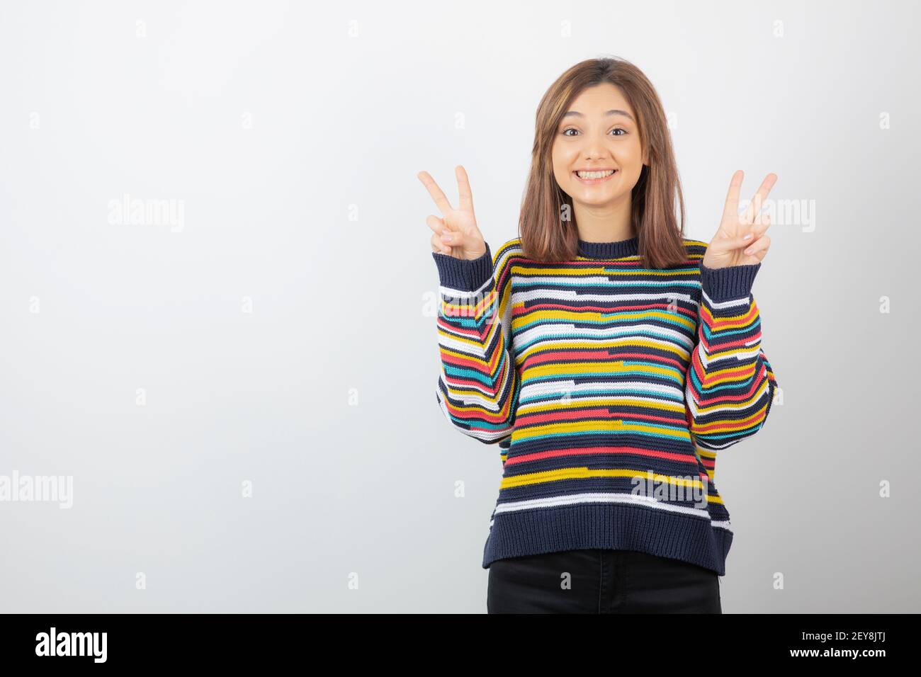 Picture of a positive cute girl model standing and showing victory sign ...
