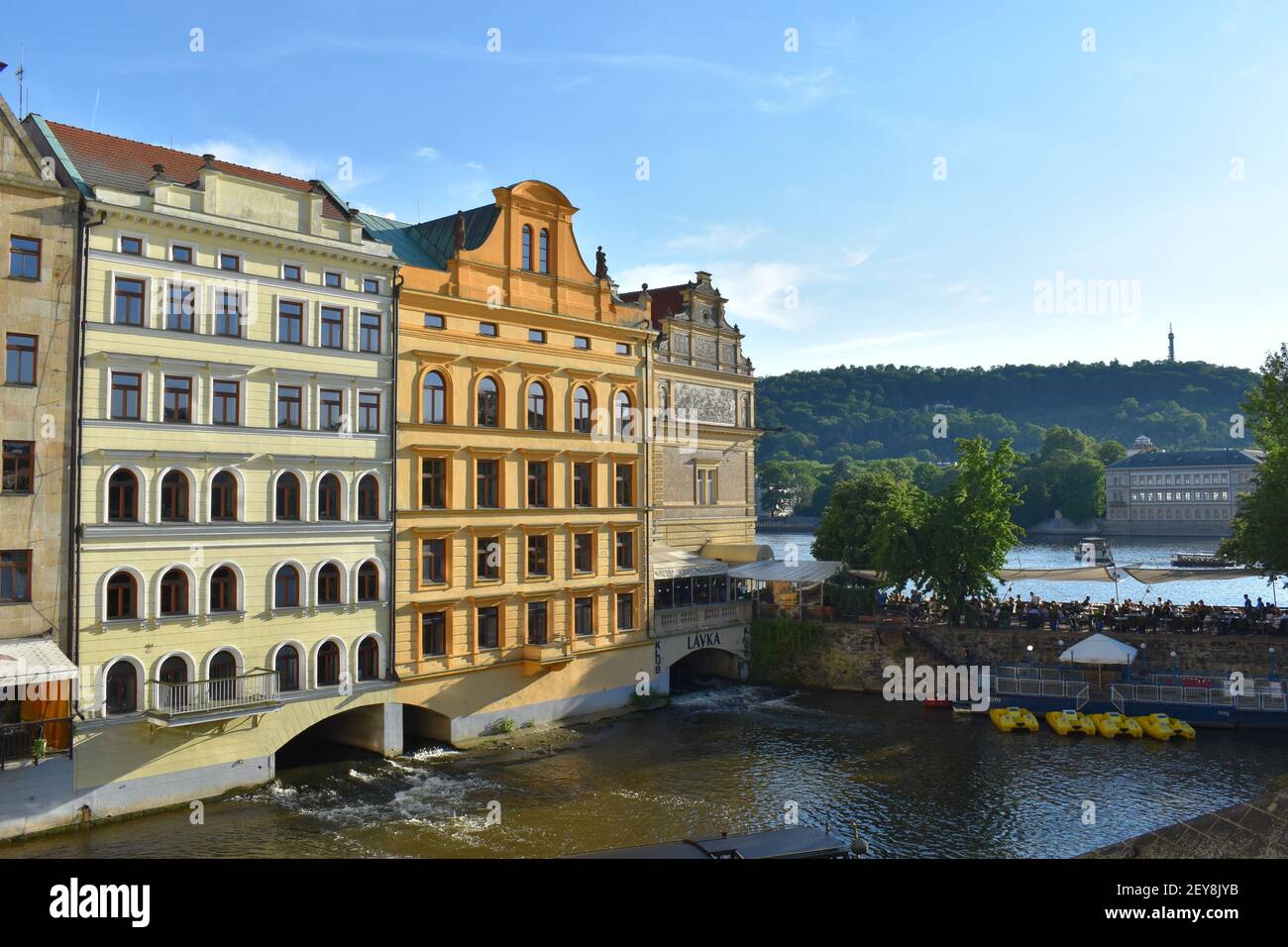 The old buildings near the river in Prague with forested mountains in a ...