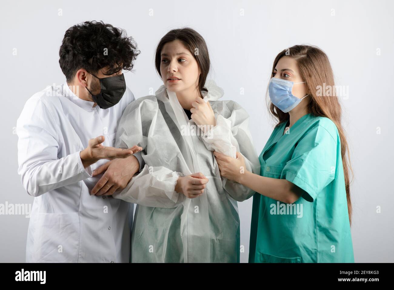 Three doctors standing and looking at each other on white background ...