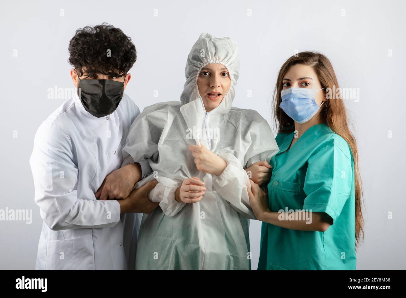 Three doctors standing and looking at camera on white background Stock ...