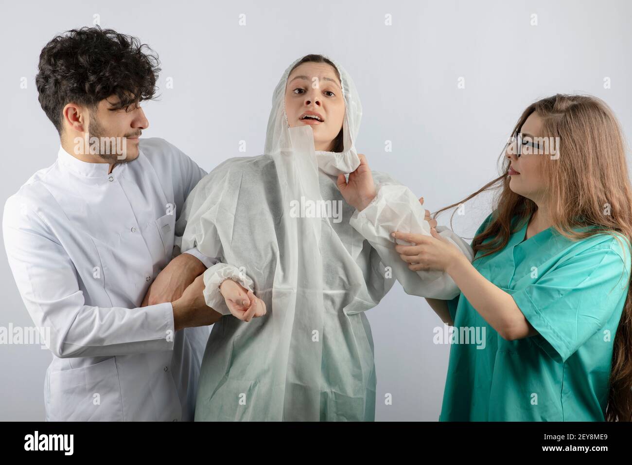 Three doctors standing and looking at each other on white background ...