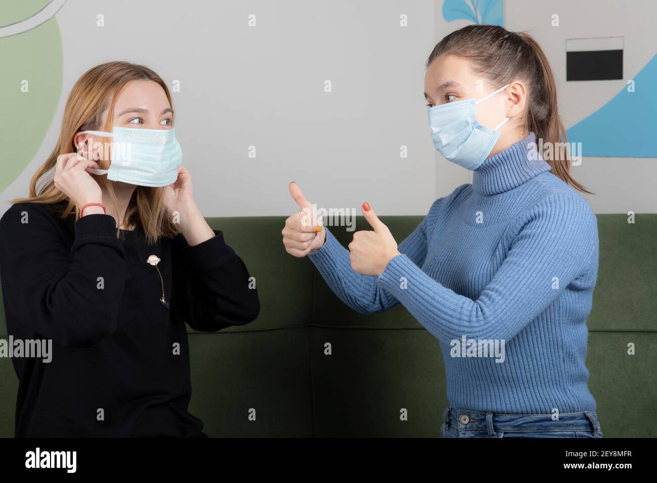 Two young women in face masks telling each other everything will be ok ...