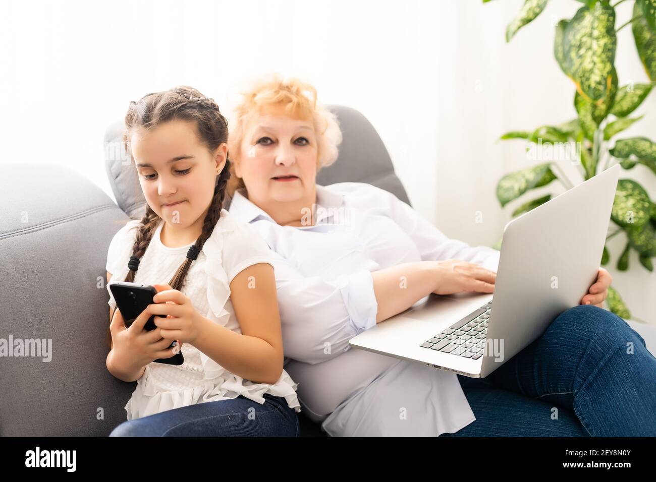 modern grandmother teaching grandchild how to use laptop computer at ...