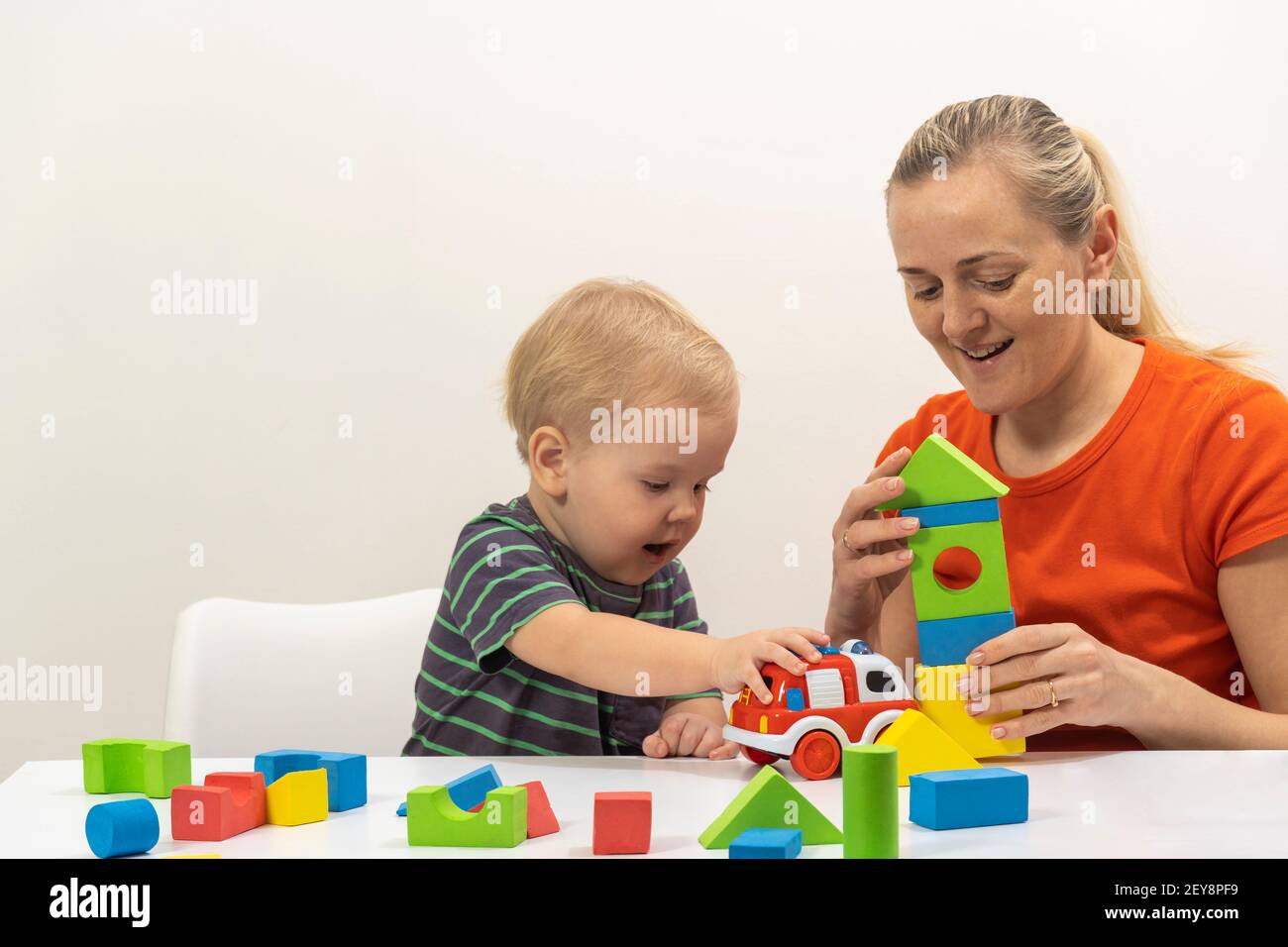 Mom and son play cubes and laugh at the bright background Stock Photo ...