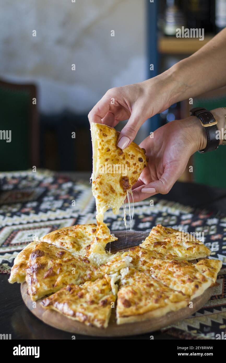 A vertical closeup shot of a hand taking a slice of delicious Georgian ...
