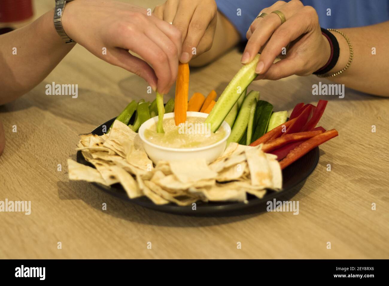 A closeup shot of people dipping vegetables in hummus Stock Photo - Alamy