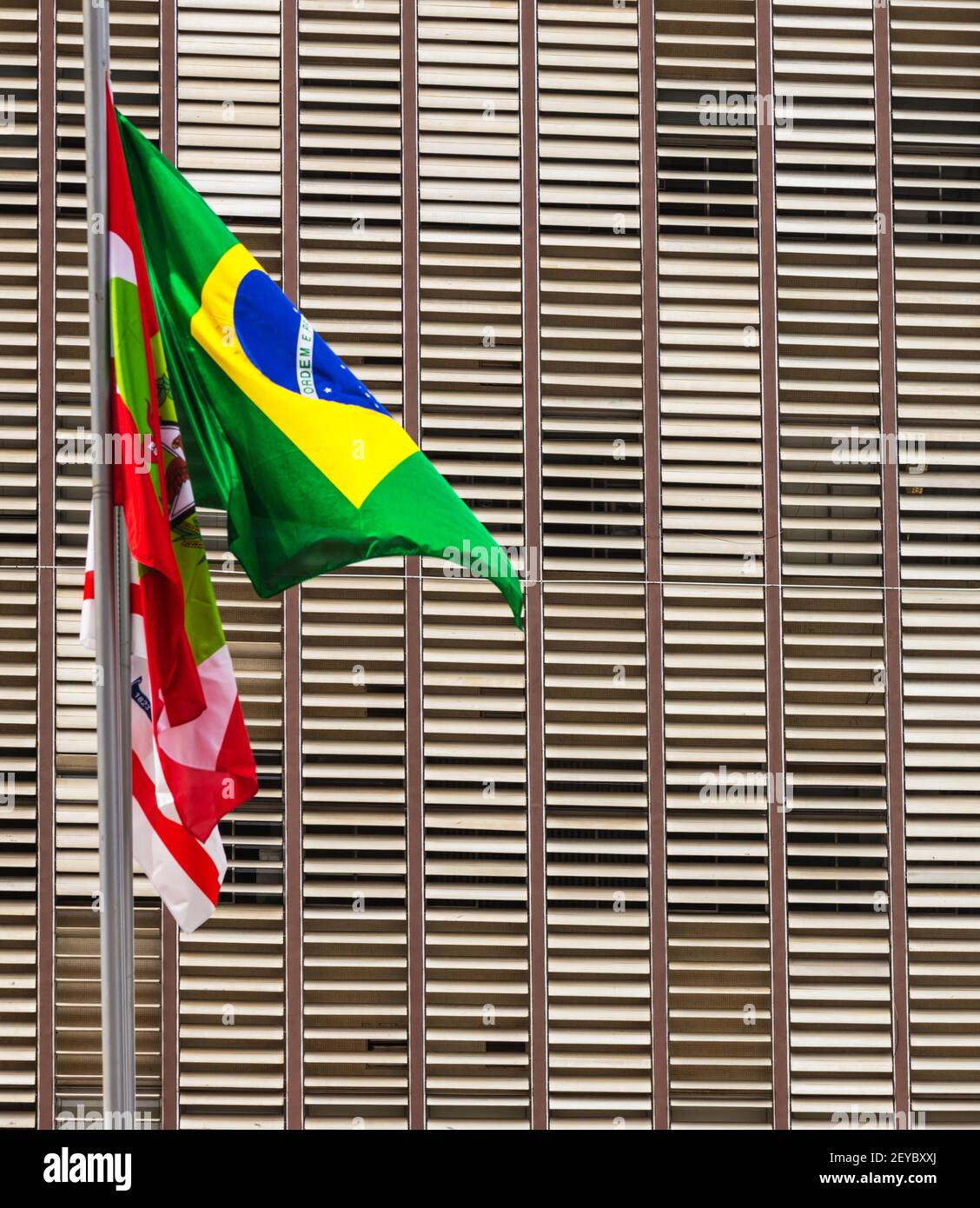 A vertical shot of multiple flags waving in front of a building Stock ...