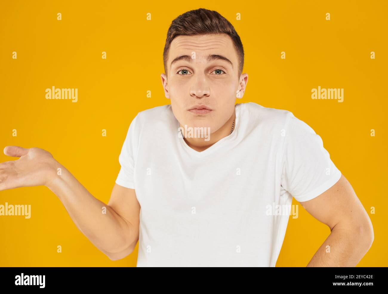 Angry guy gesturing with his hands on a yellow background cropped view ...