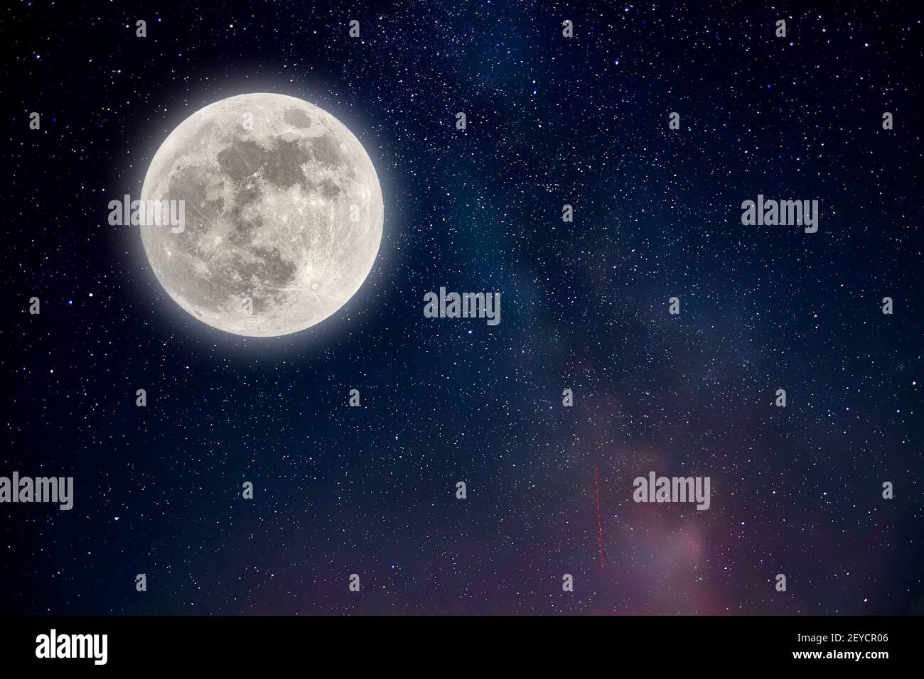 A low angle shot of the bright moon shining in the colorful and starry ...