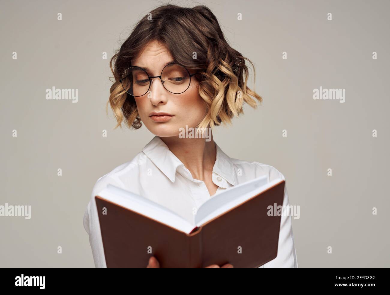 Literate woman with book in hands and in glasses white shirt education ...