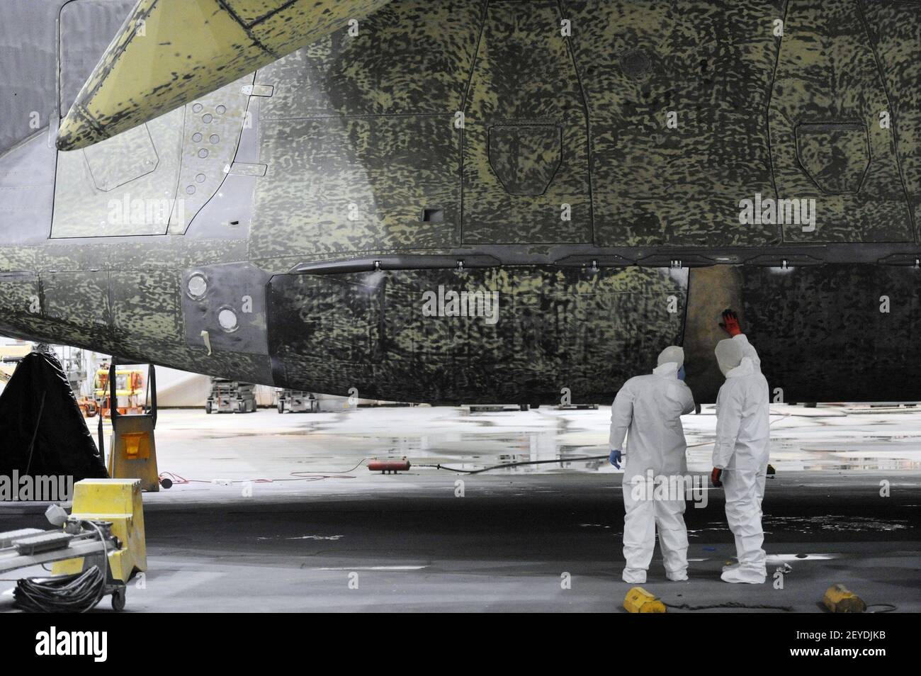 Workers inspect already sanded spots on the fuselage of the C-17 in for ...
