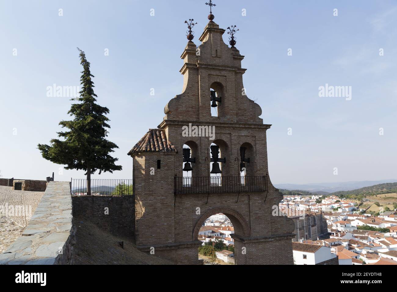 A medieval tower with an arc and black bells on it and a cityscape ...