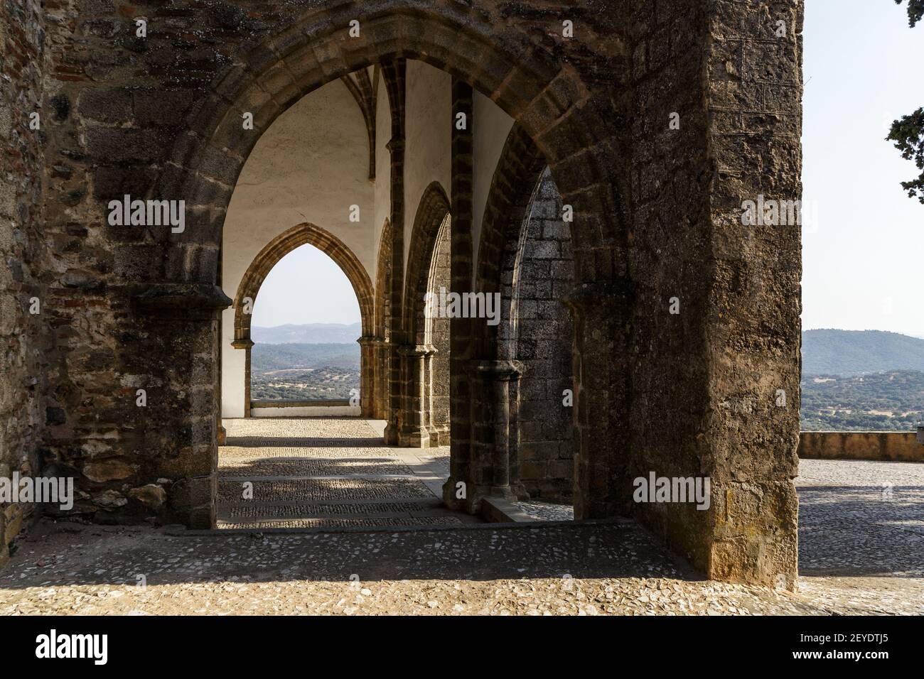 A medieval stone building and a cityscape visible through its big arcs ...