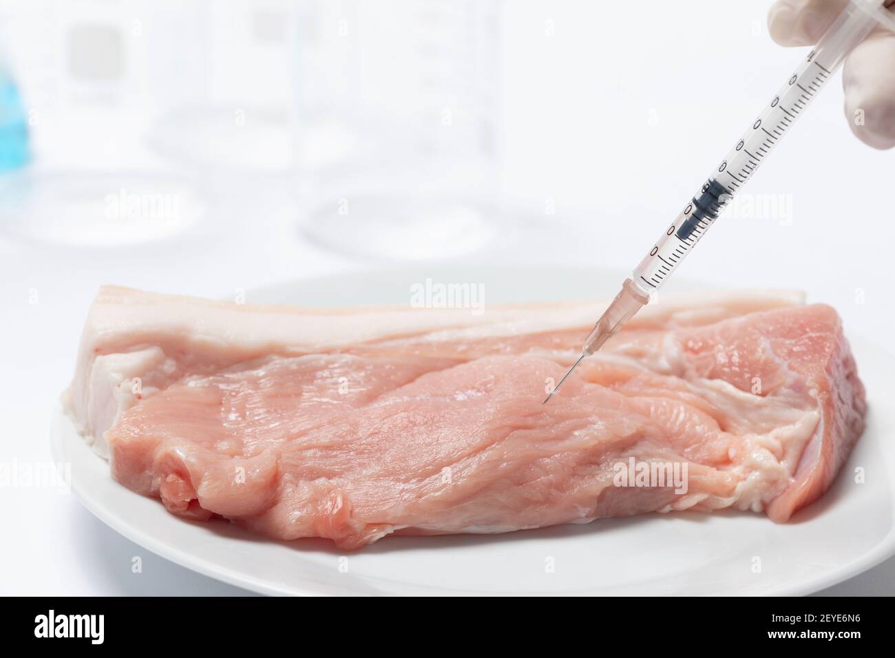 A closeup of a scientist injecting toxic substances to a raw piece of ...