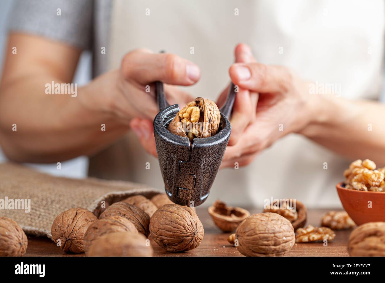 A caucasian woman is using walnut pliers ( a cast iron nutcracker tool ...