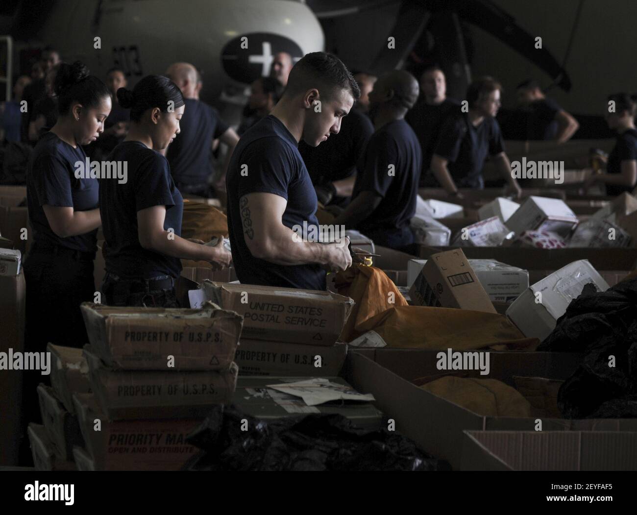 U.S. Sailors sort through mail in the hangar bay aboard the aircraft ...