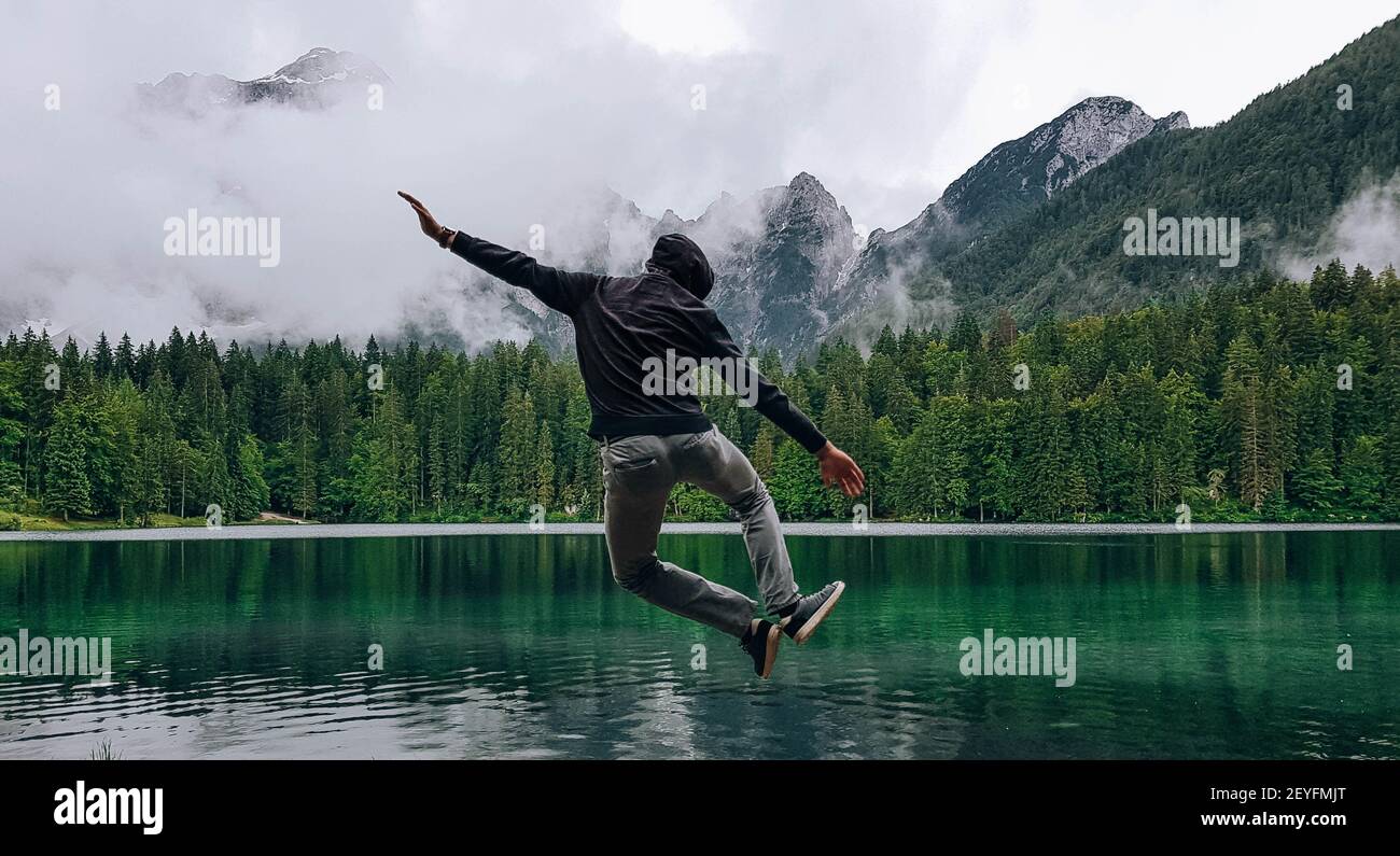 A shallow focus of a person jumping and heel kicking near a lake ...