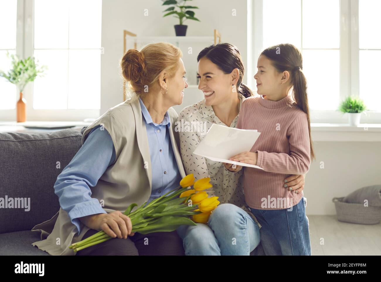 Senior Lady Getting Flowers From Loving Daughter And Granddaughter On