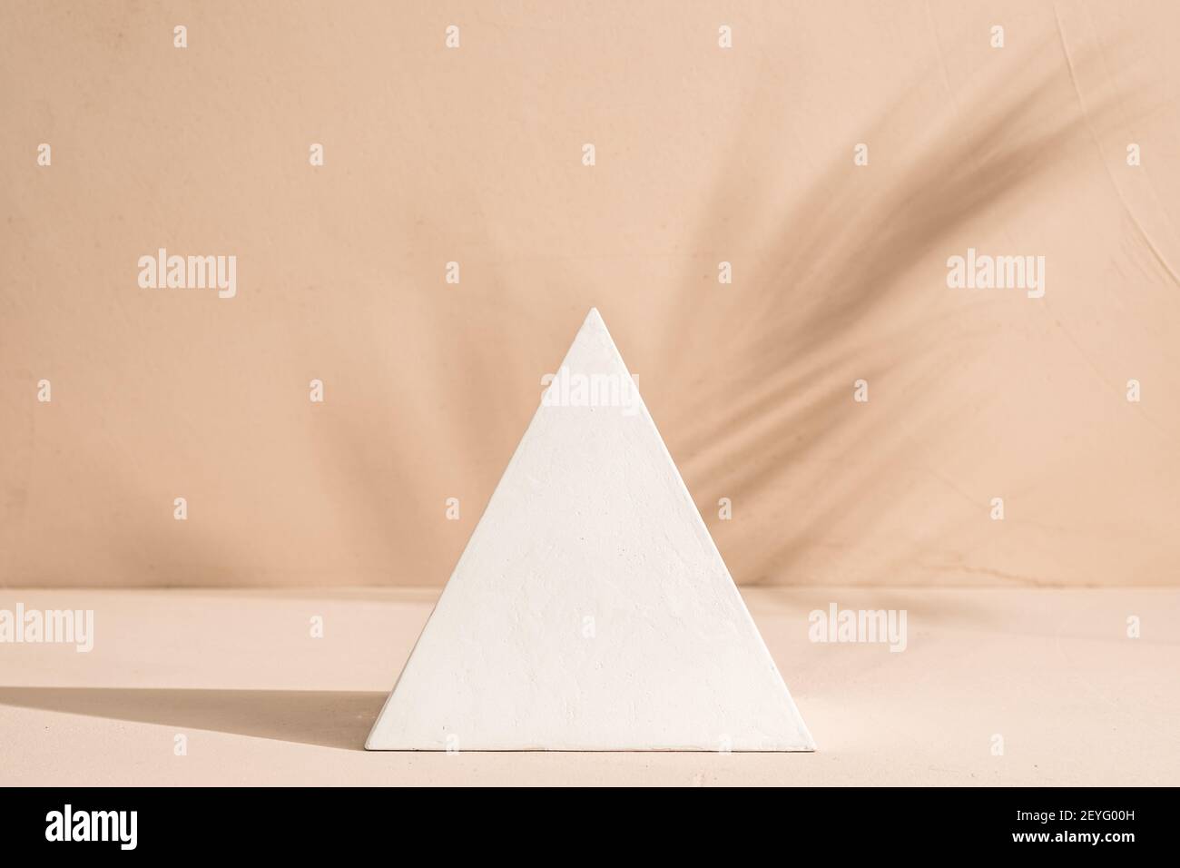 Gypsum pyramid in sunlight and palm leaf shadow on clay wall background ...
