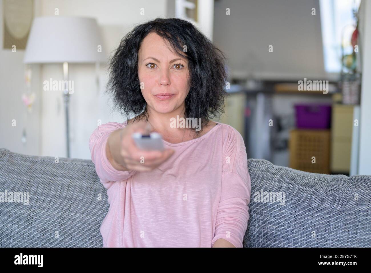 Smiling woman controls the television with the remote control Stock ...