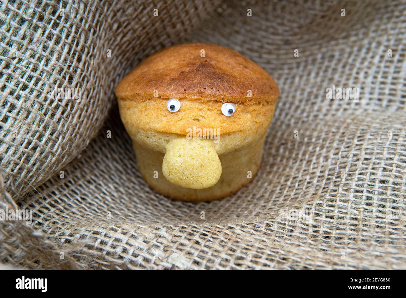 Homemade muffin with a big nose and small eyes on a burlap cloth. Cute ...