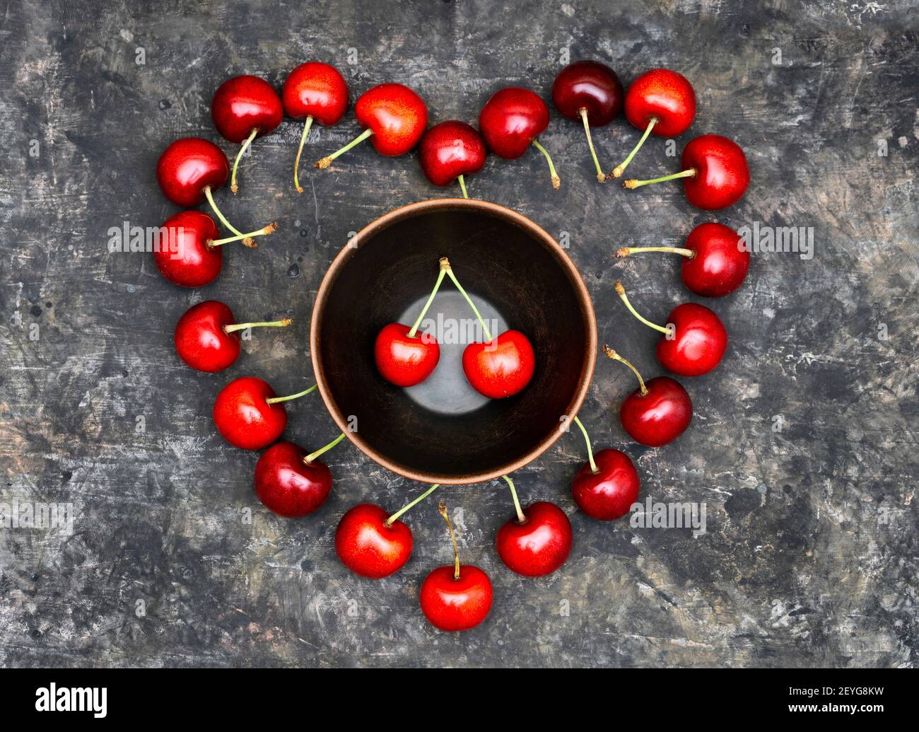 Red heart symbol made of ripe sweet cherries with a bowl in the center ...