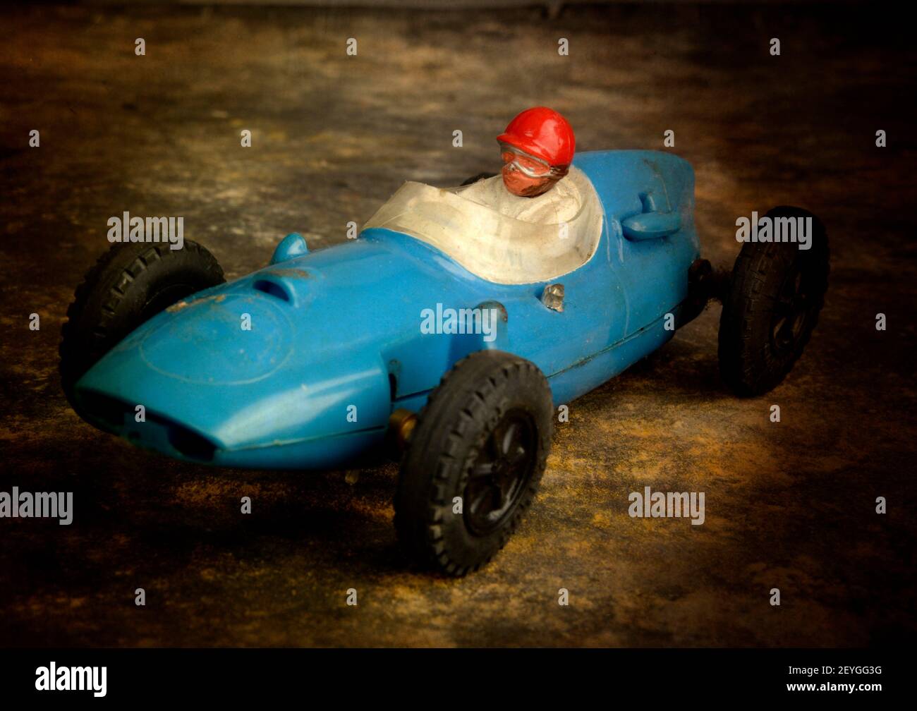 A classic blue racing car model with a driver in a red helmet on a ...