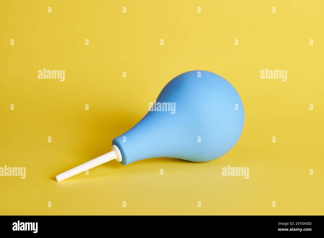 Studio shot of a blue medical rubber constipation enema on yellow ...