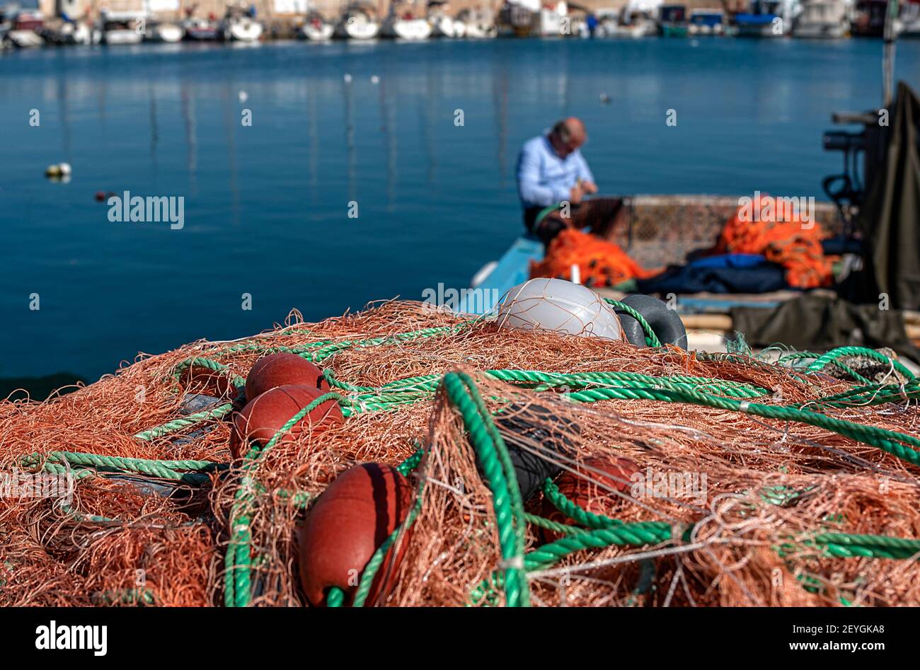 Fisherman repairing nets behind fishing nets Stock Photo - Alamy