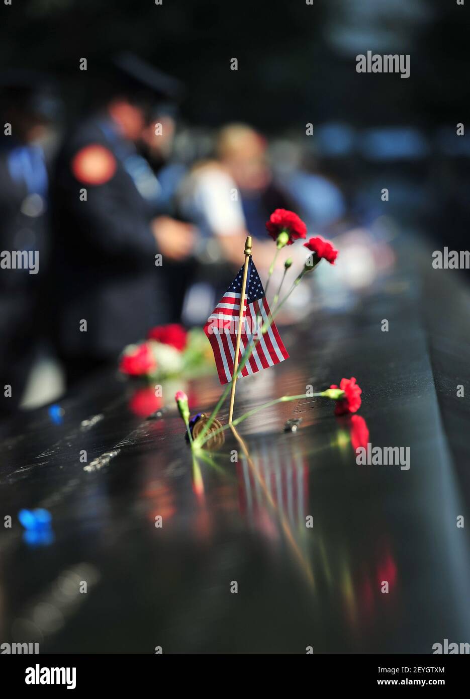 A flag and flowers on the South reflecting pool at the 9/11 Memorial ...