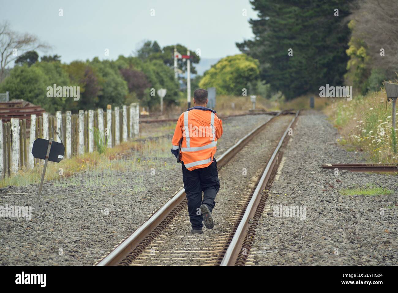 Perspective view of railroad worker walking away between rail tracks ...