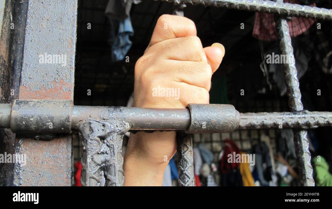 An inmate grasps a bar at an overcrowded police lockup facility on the ...