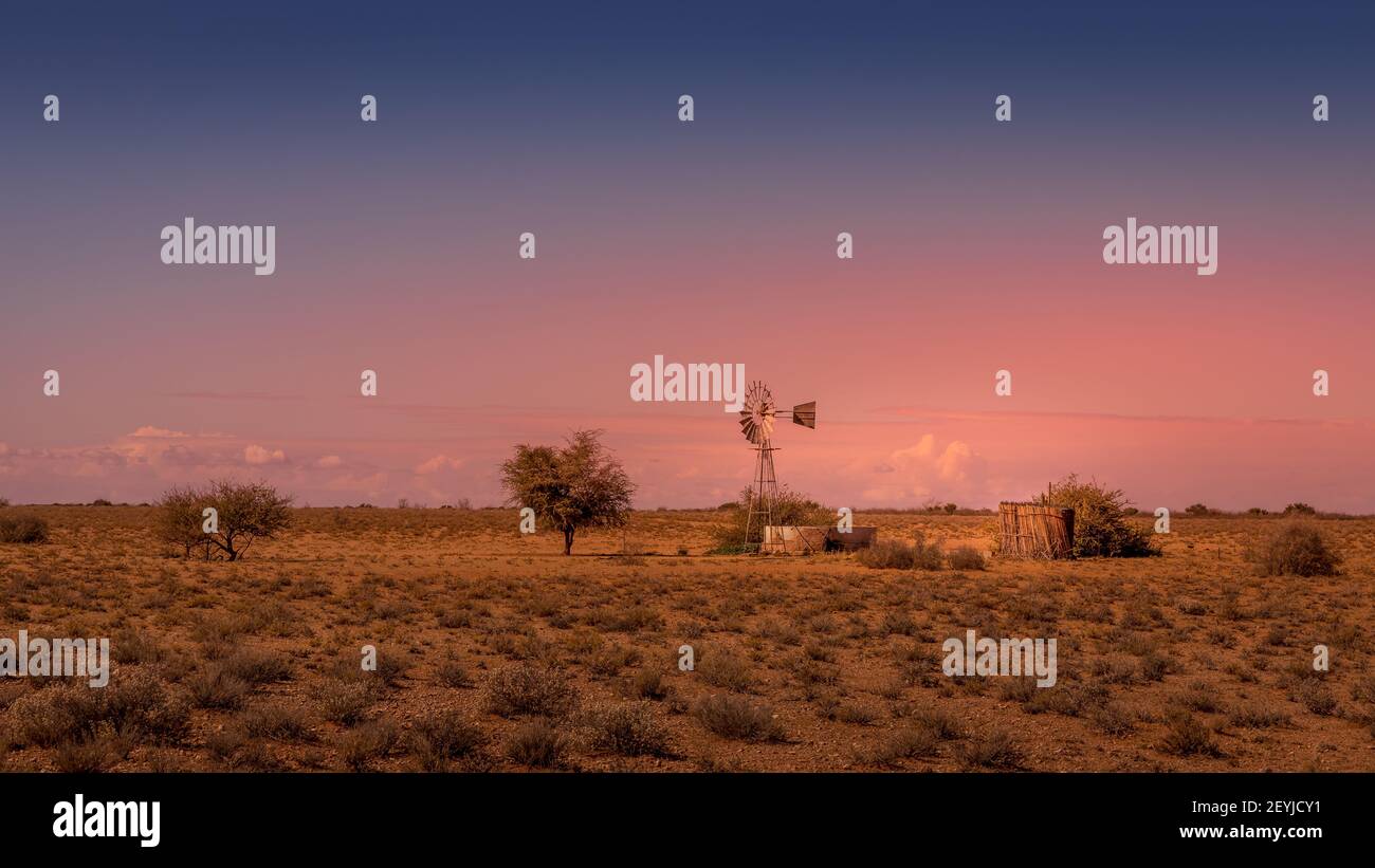 Windmill in a breathtaking landscape at sunset in the Kalahari desert ...