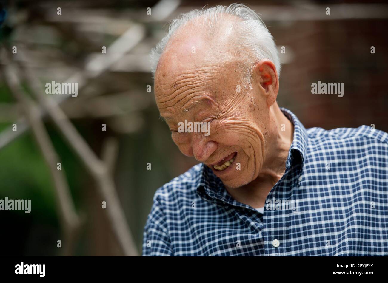 Hok Kun Ng, 89, of Overland Park, laughs as he watered his backyard ...