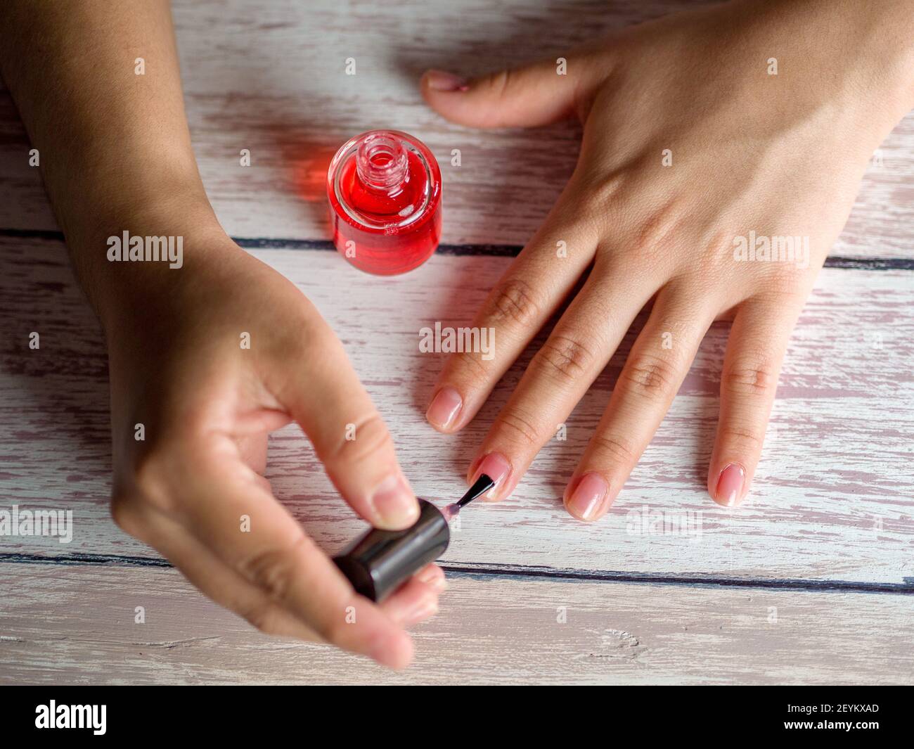 A woman applying a red treatment oil for nails Stock Photo - Alamy
