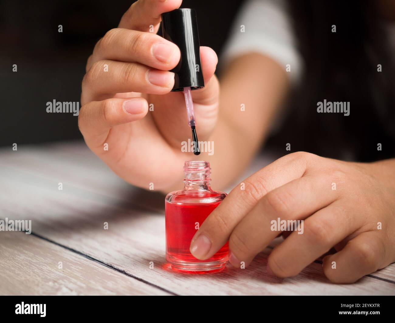 A woman applying a red treatment oil for nails Stock Photo - Alamy