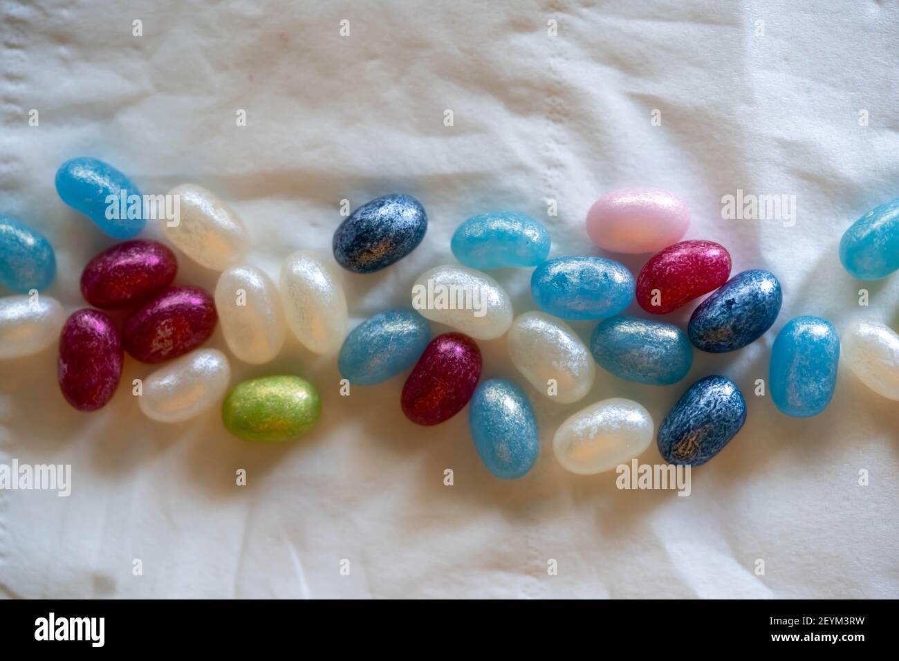 Colorful candy beans placed on top of a white background crumpled paper ...