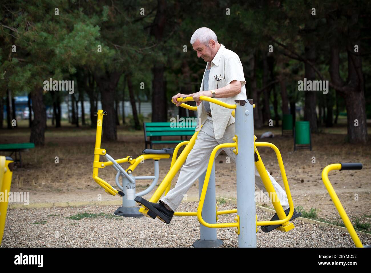 Old man making exercises on outdoor gym against green summer park as a ...