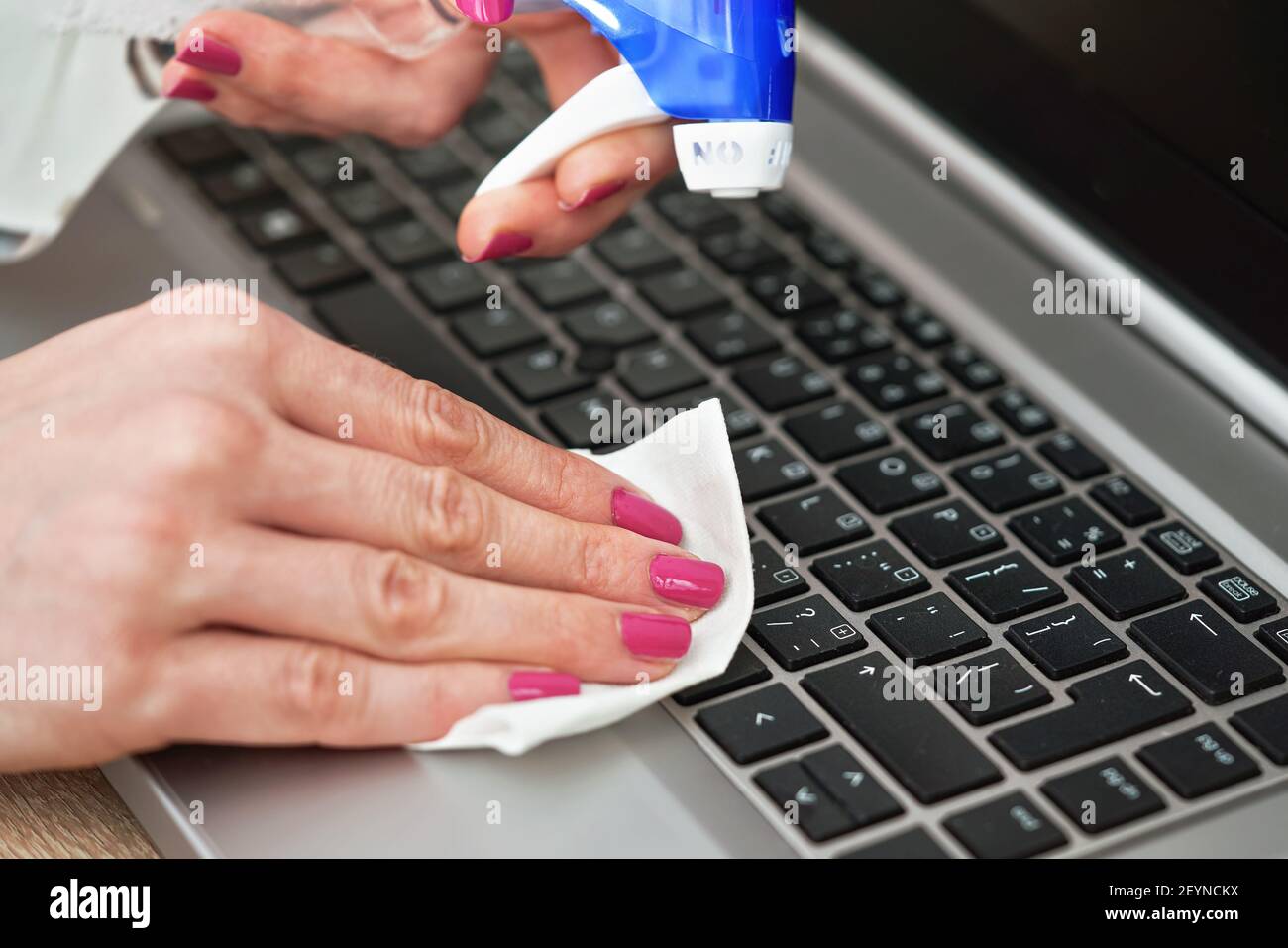 Woman cleaning laptop keyboard with white tissue, detail on her fingers ...