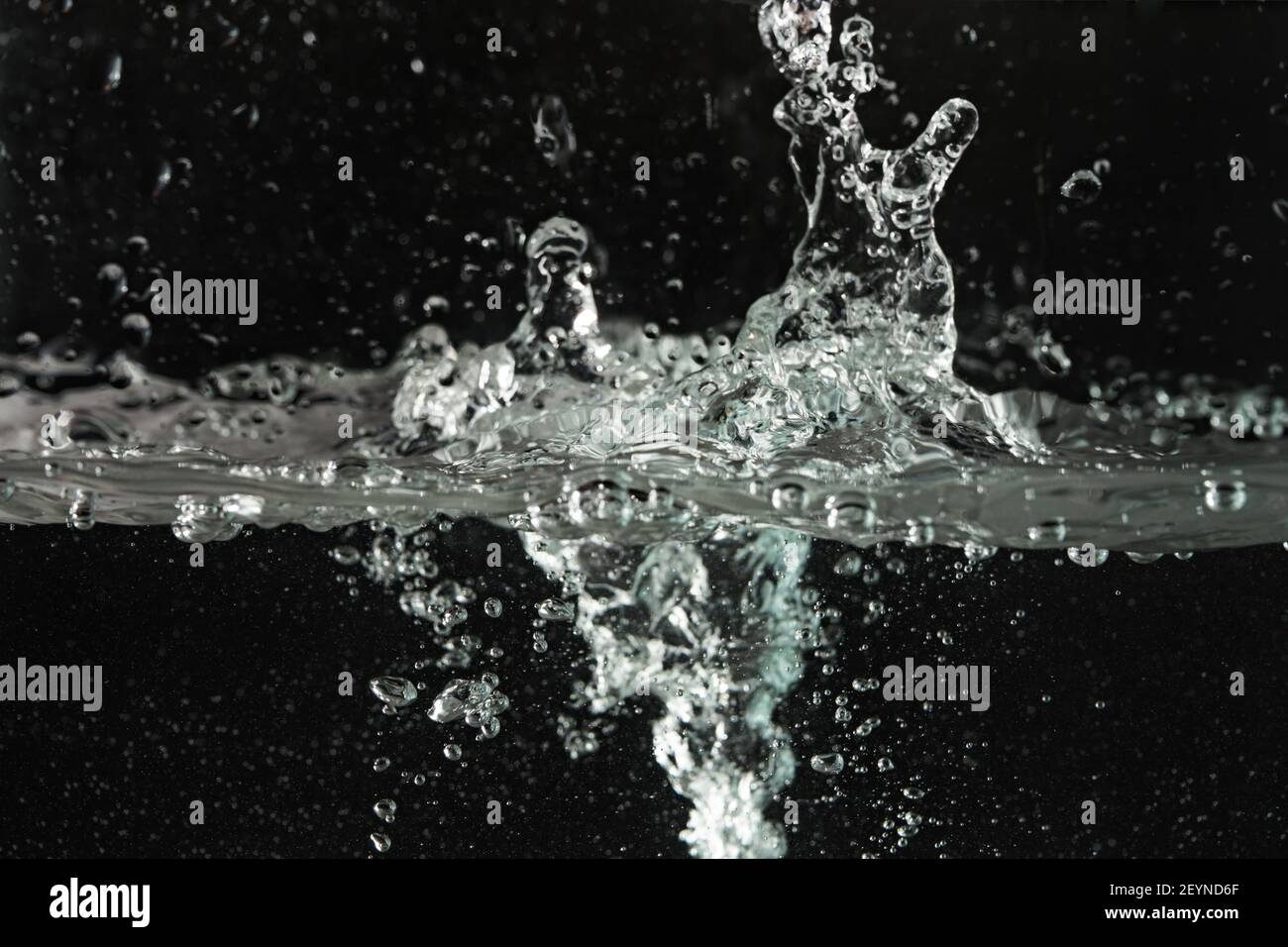 Water splashing as it's poured into aquarium tank, black background ...
