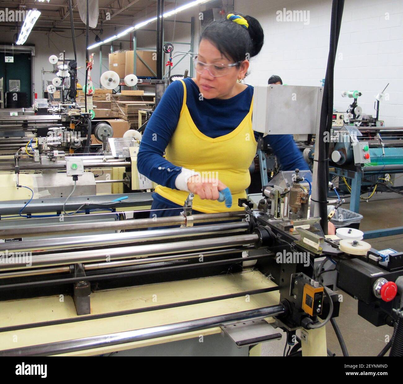 A worker stretches a string at the D'Addario & Co. plant in Farmingdale ...