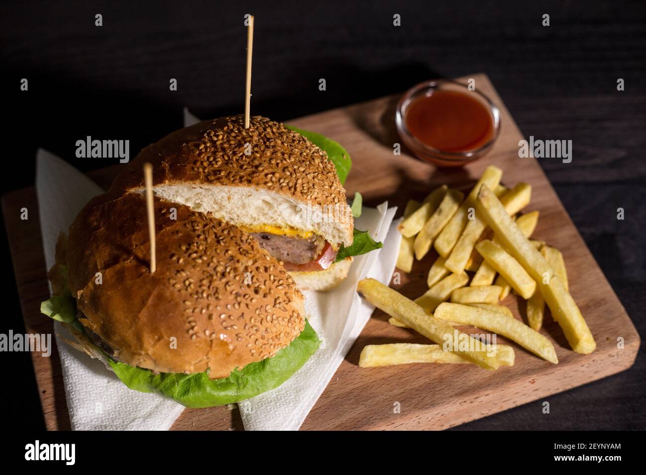 A high angle closeup of a sliced hamburger with french fries and ...
